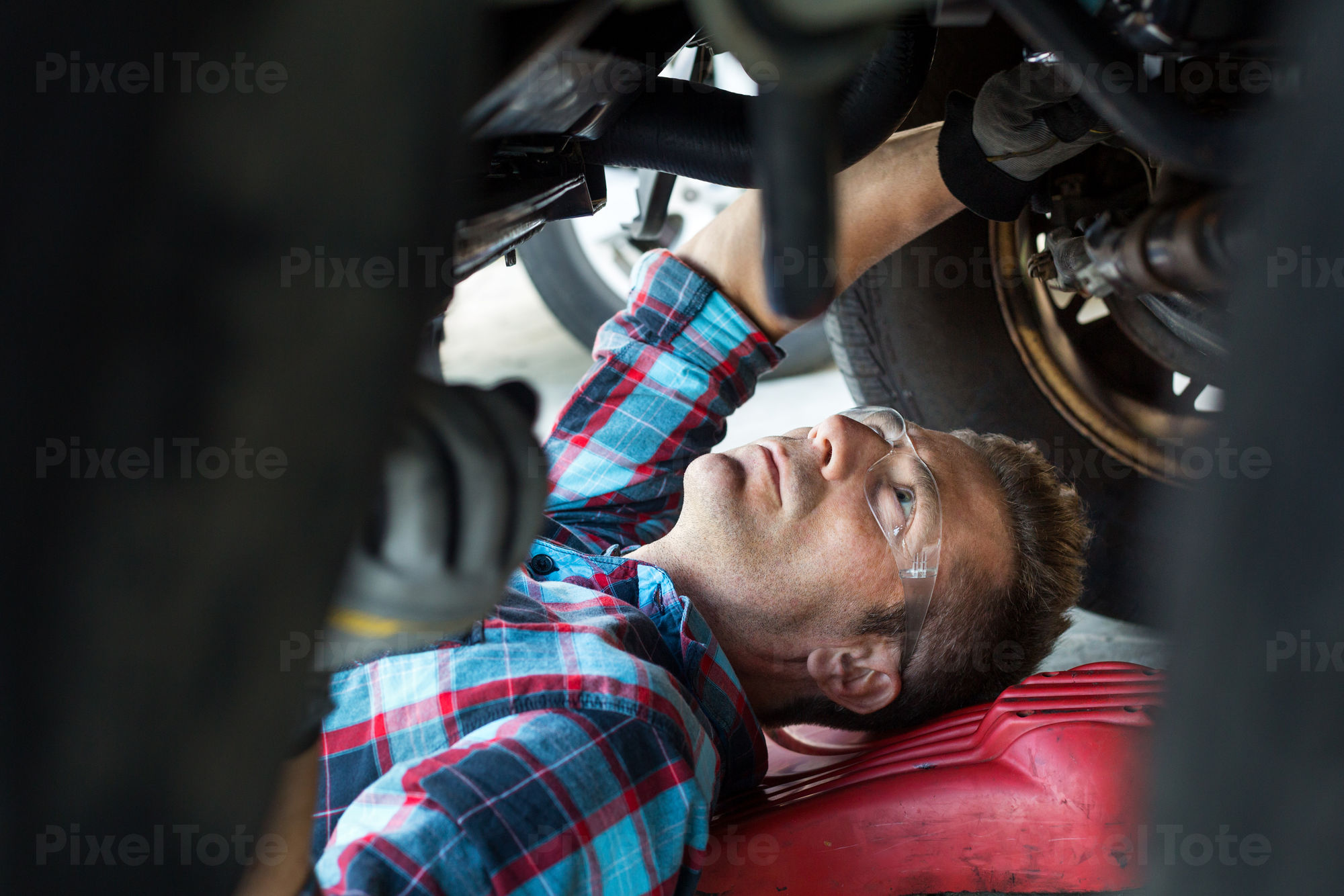 Car Mechanic Laying on a Creeper Stock Photo - PixelTote