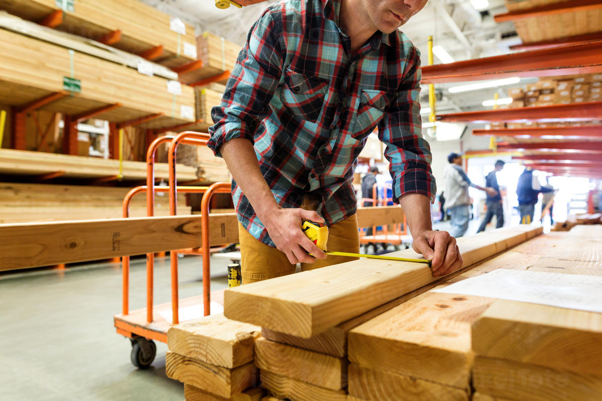 Man Measuring a Wood Board in Editorial Photo - PixelTote