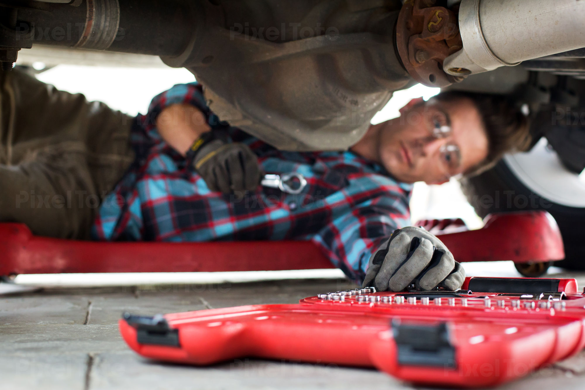 Auto Mechanic Laying on a Creeper Stock Photo - PixelTote