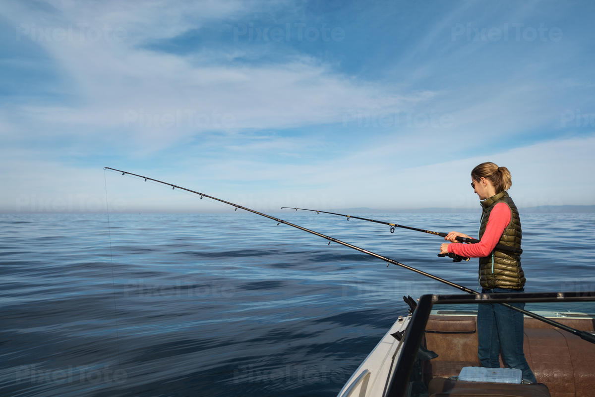 Young Woman Fishing from a Boat Stock Photo - PixelTote