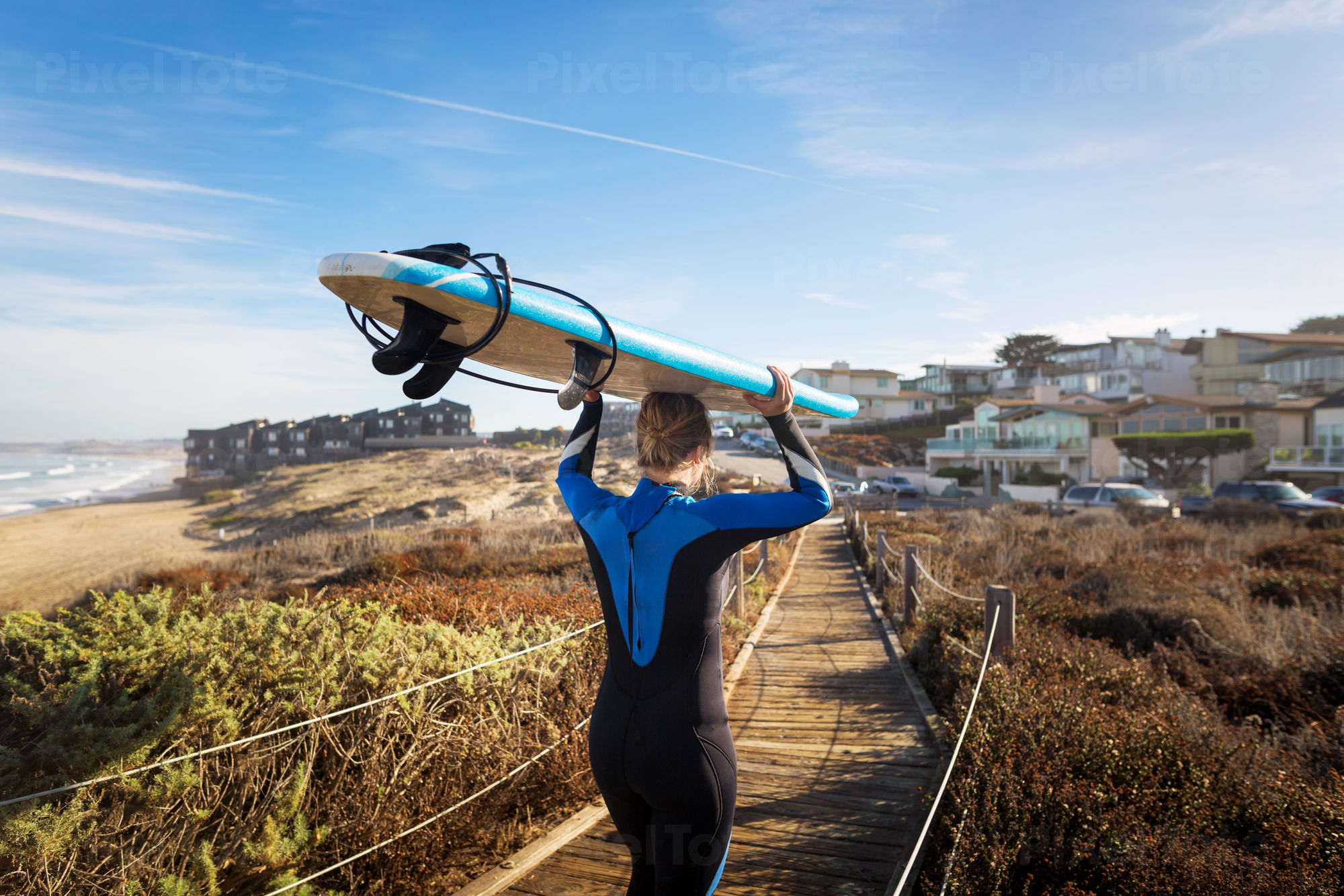 Young Woman Carrying a Surfboard Stock Photo - PixelTote