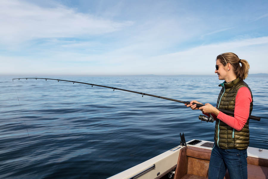 Smiling Woman Fishing from a Stock Photo - PixelTote