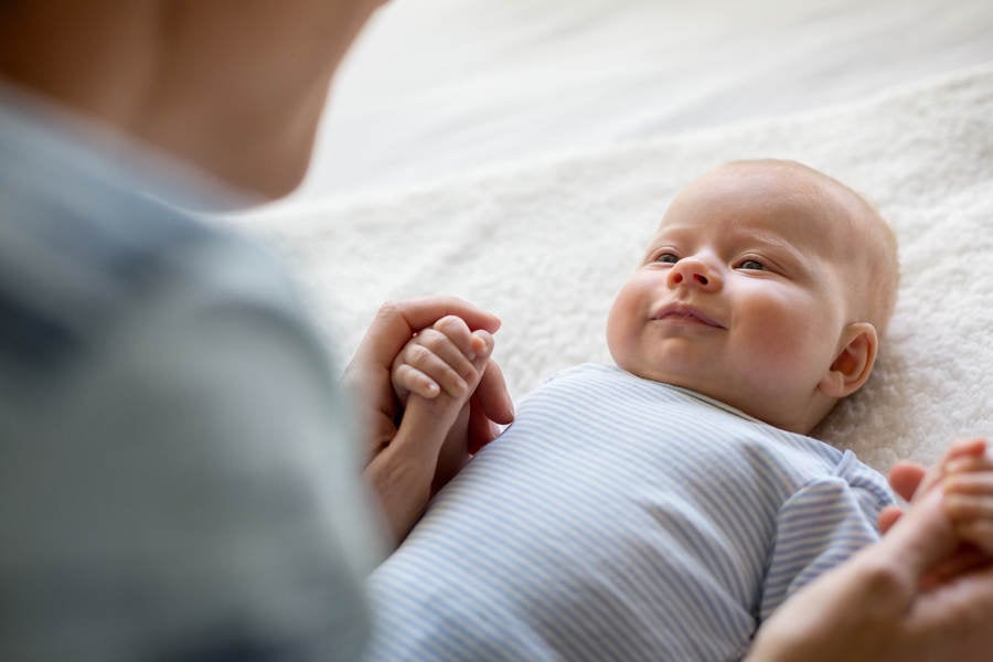 Baby Girl Snuggling with Her Mom and Looking at the Camera Stock Photo