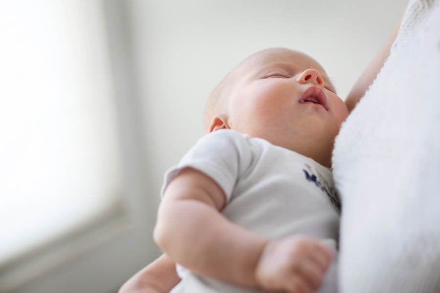 Baby Girl Snuggling with Her Mom and Looking at the Camera Stock Photo